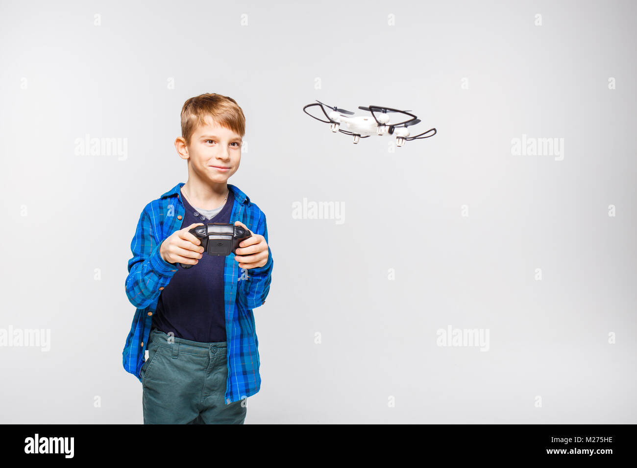 Cute boy operating the dron or quadcopter by remote control on grey ...