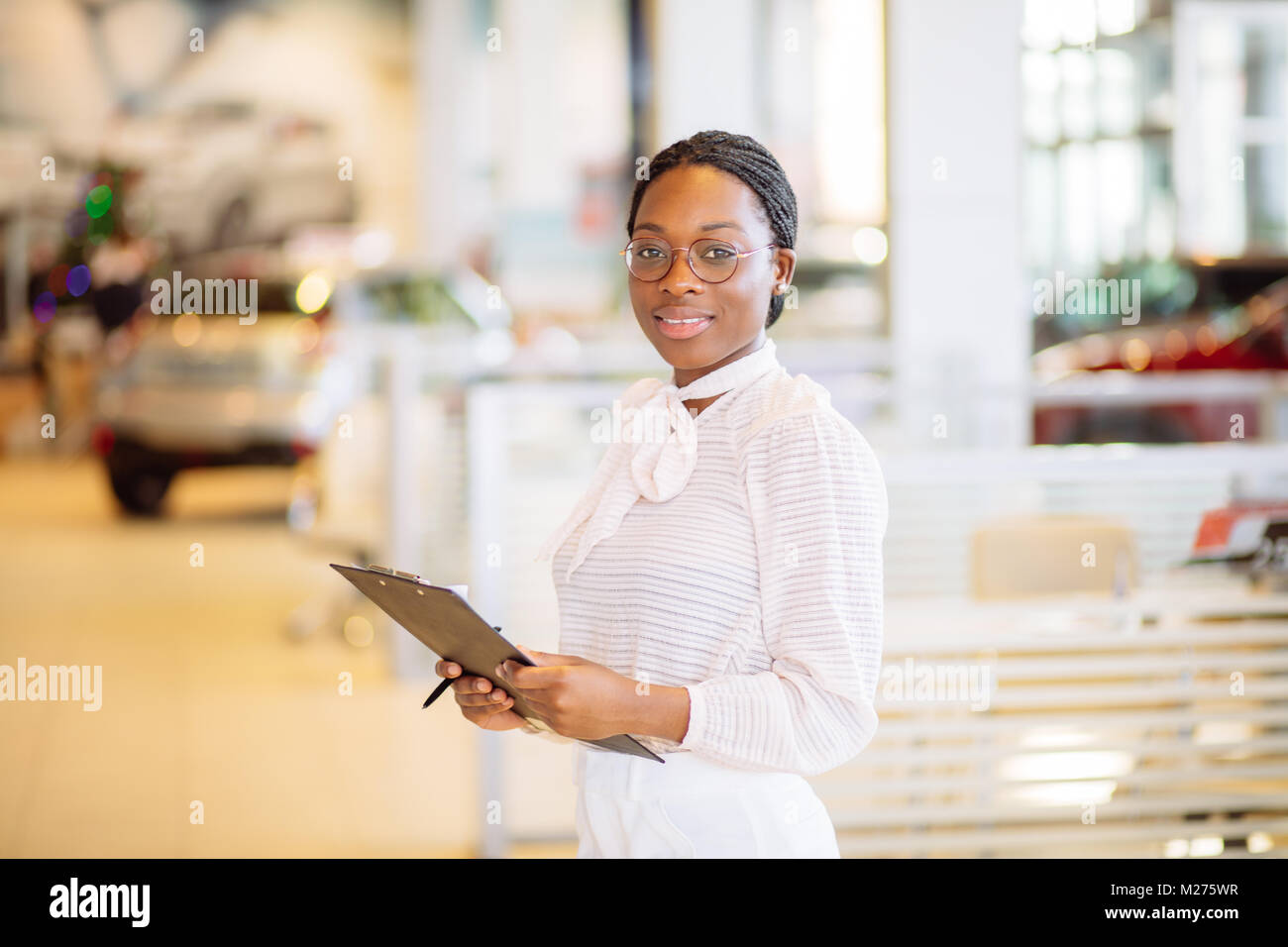 Professional female salesperson working in car dealership Stock Photo ...