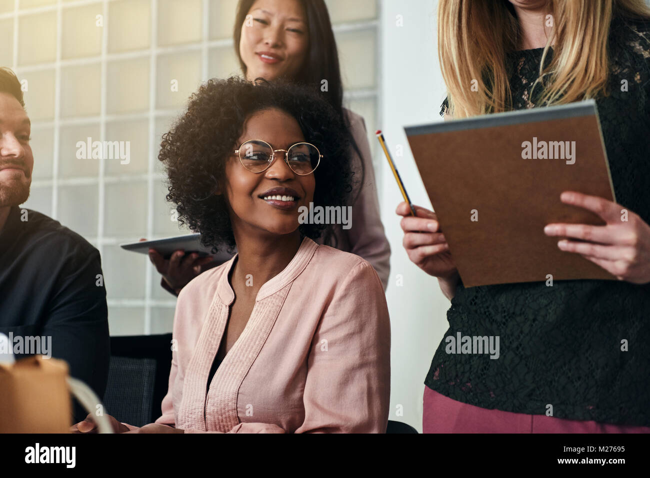 Diverse group of smiling coworkers talking while working together ...