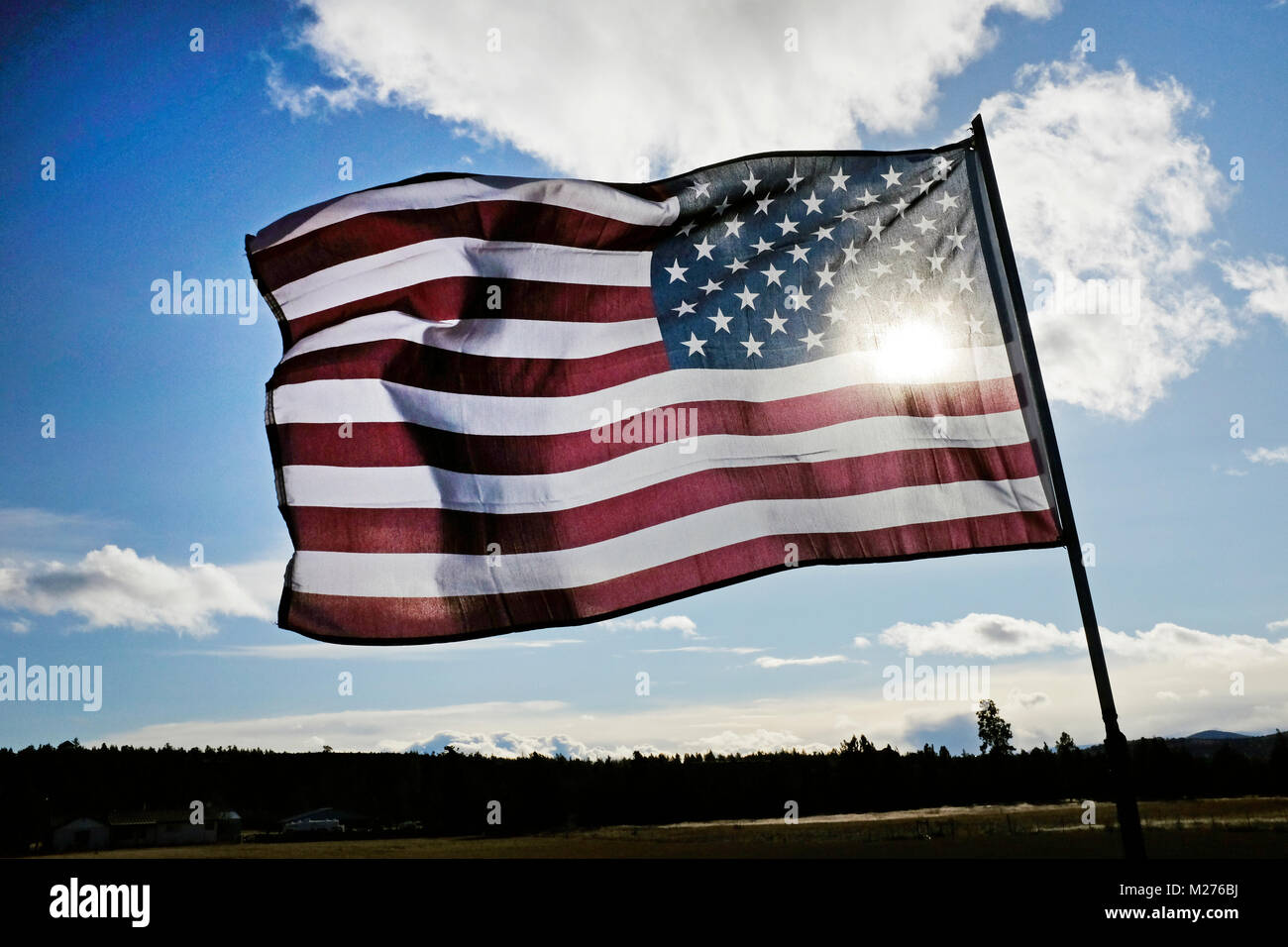 An American flag flying in a stiff breeze at the entrance to a rural ...