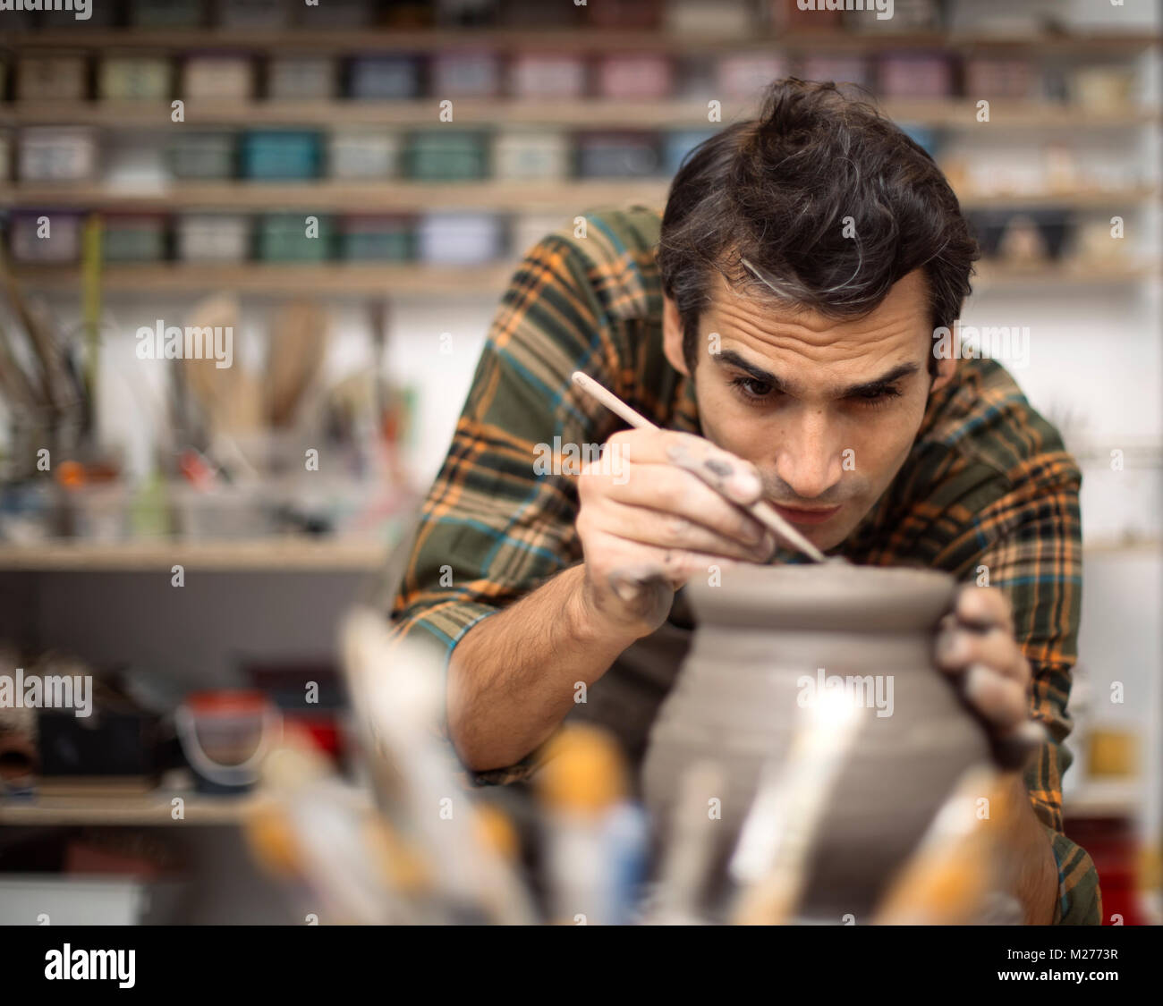 Young man making and decorating pottery in workshop Stock Photo - Alamy