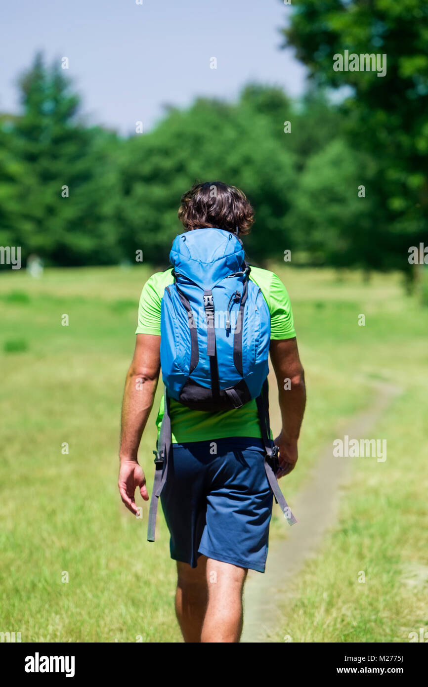 Back view at young man with backpack hiking at green nature Stock Photo ...
