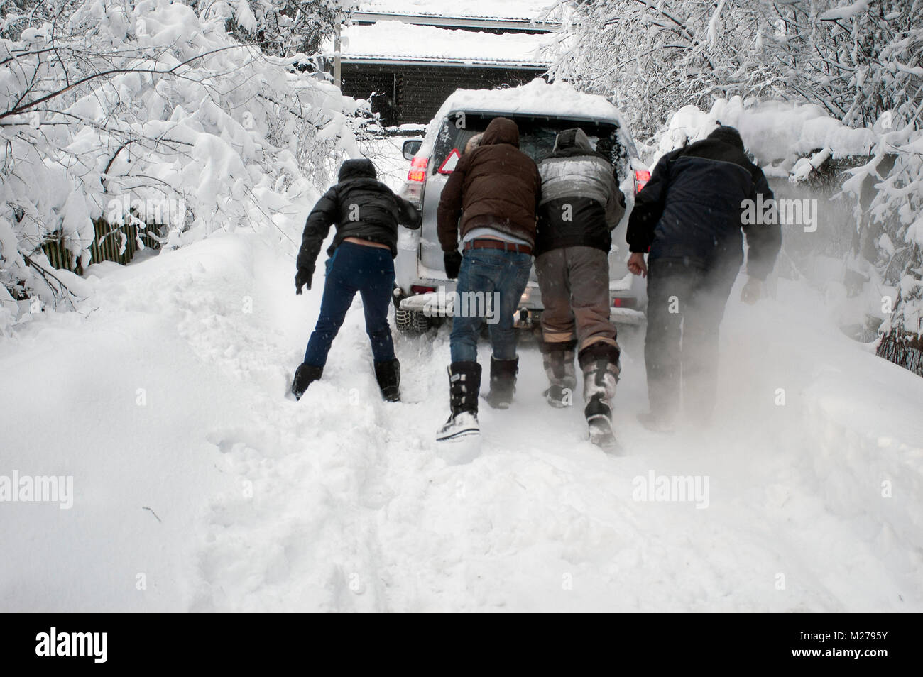 Group of men pushing the vehicvle trapped in snow, outdoor blurred ...
