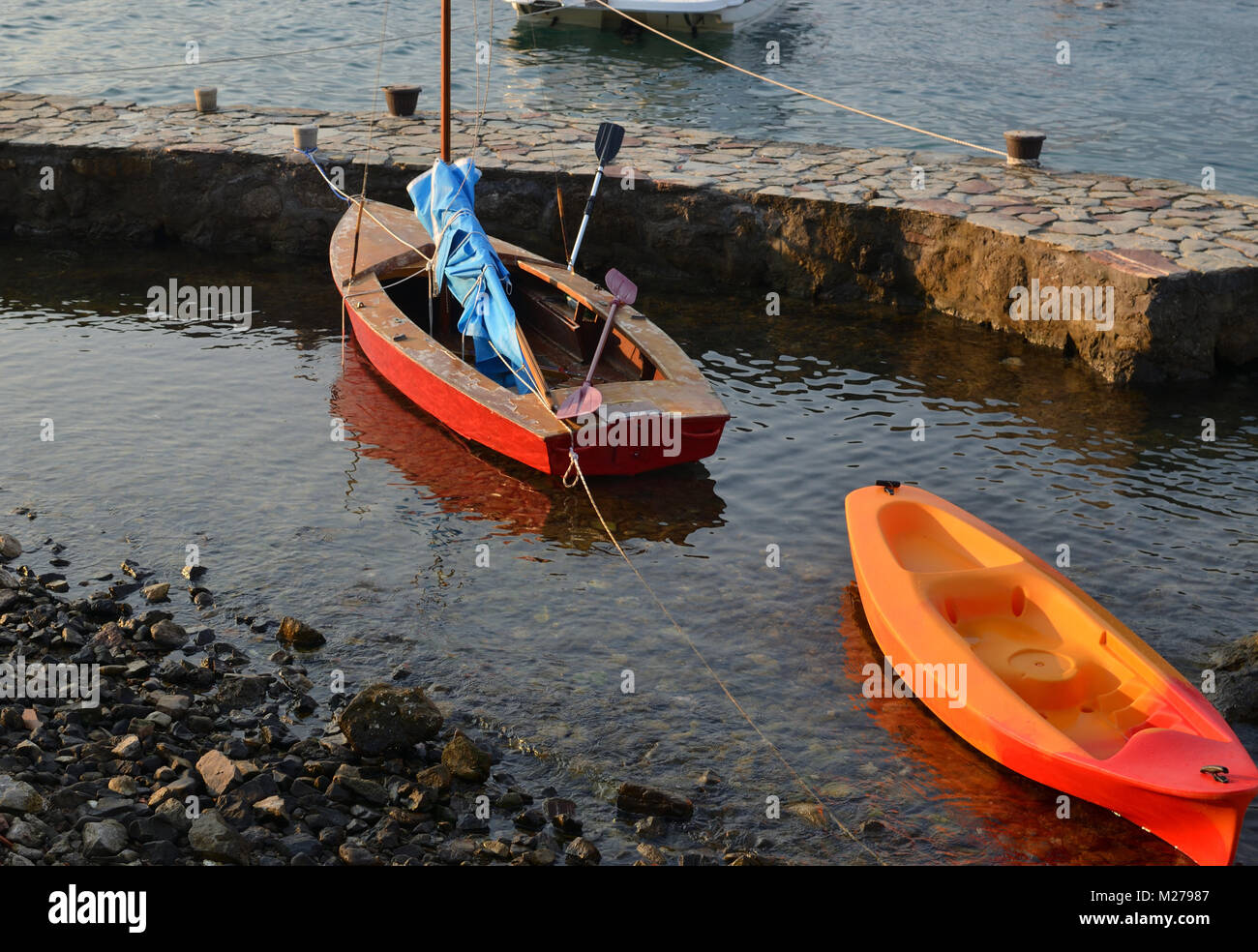 Red and orange small boat anchored close to a dock Stock Photo - Alamy