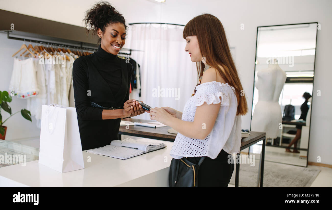 Customer shopping designer wear at a fashion boutique. Customer making ...