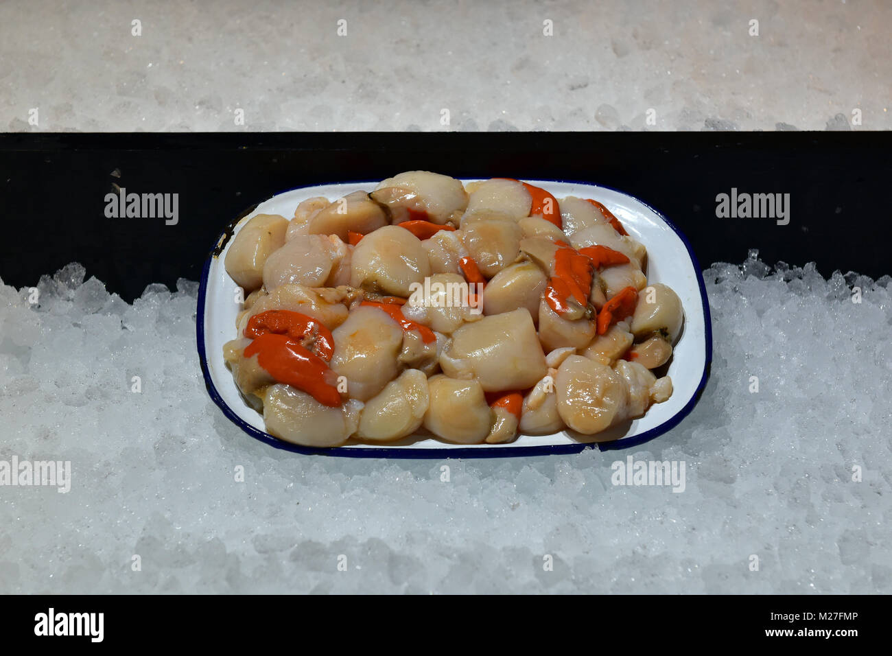 a white and blue traditional enamel serving bowl full of fresh scallops ...