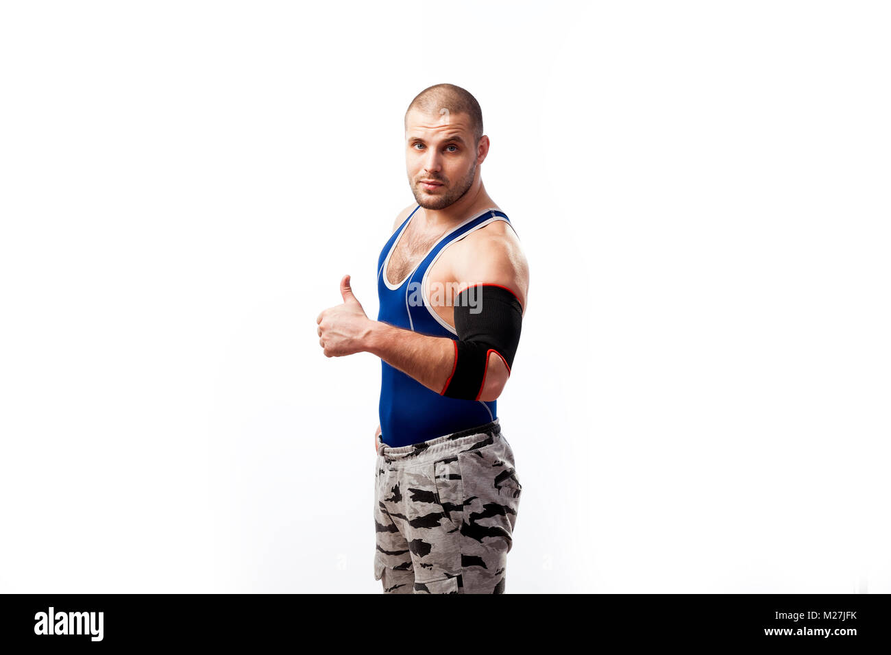 Young athletic male wrestler in blue shirt, sport pants and elbow pads ...