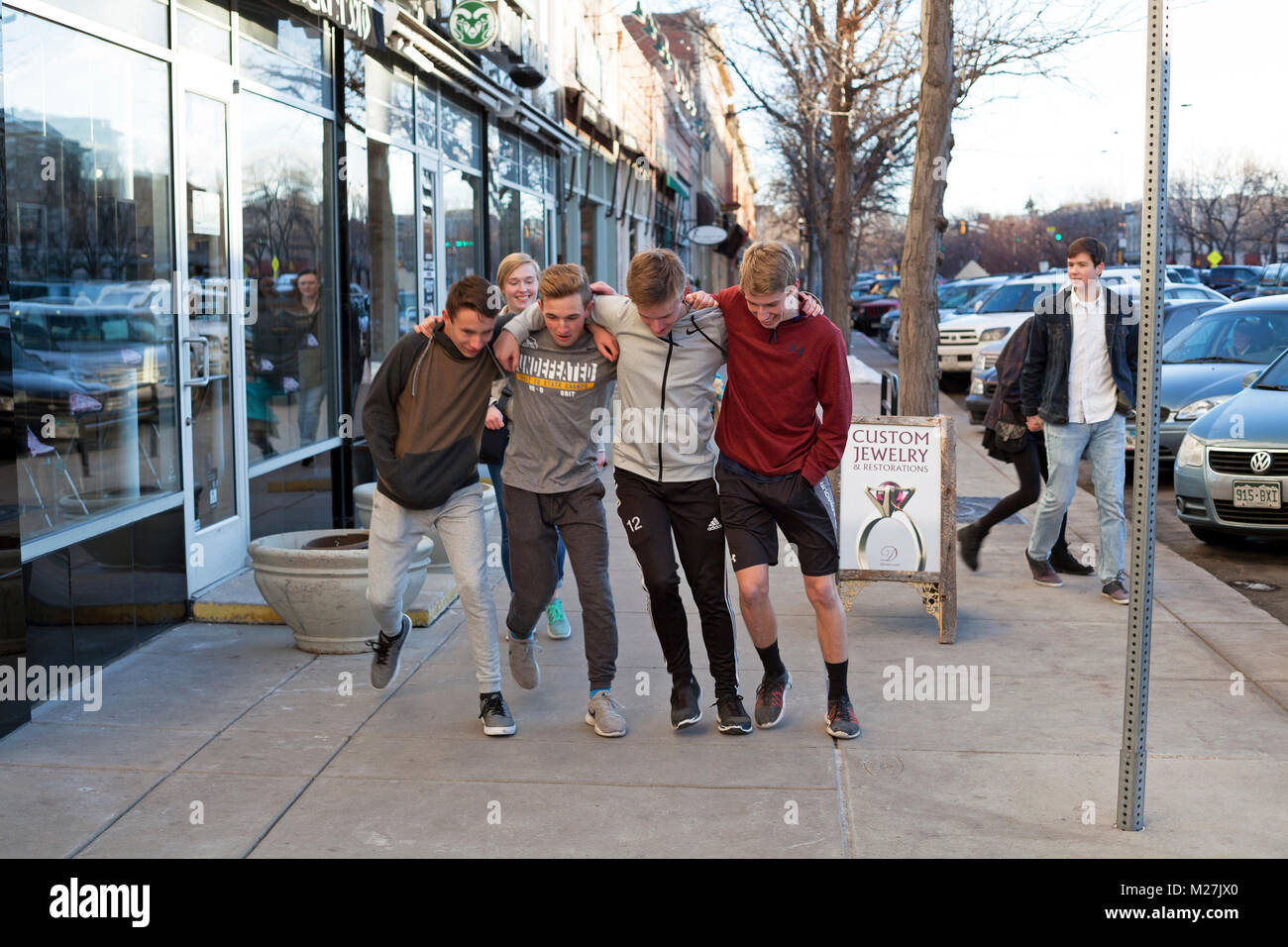 A group of friends locks arms and sidestep down the sidewalk in Fort ...
