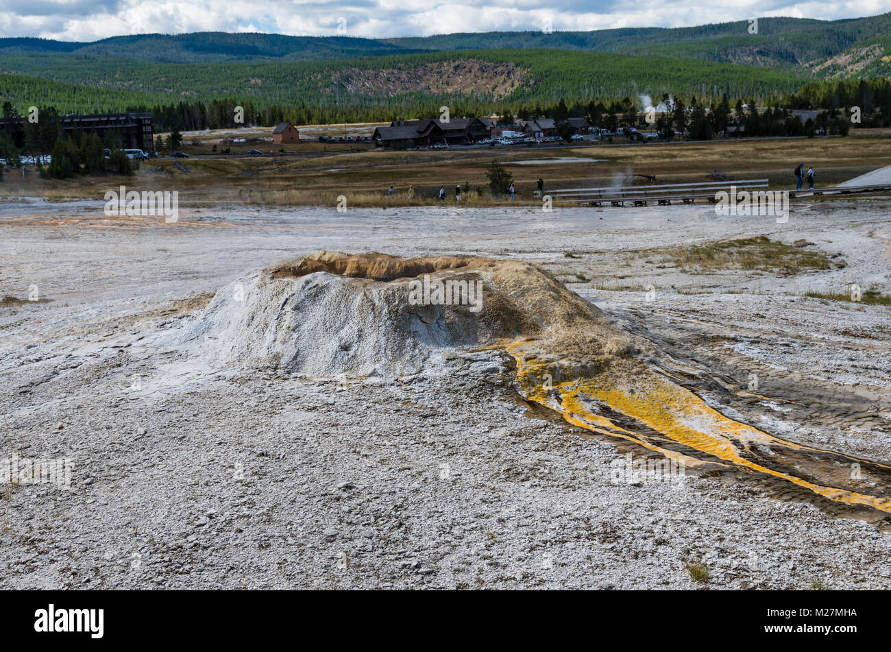 A small geyser cone with Old Faithful Lodge in the background ...