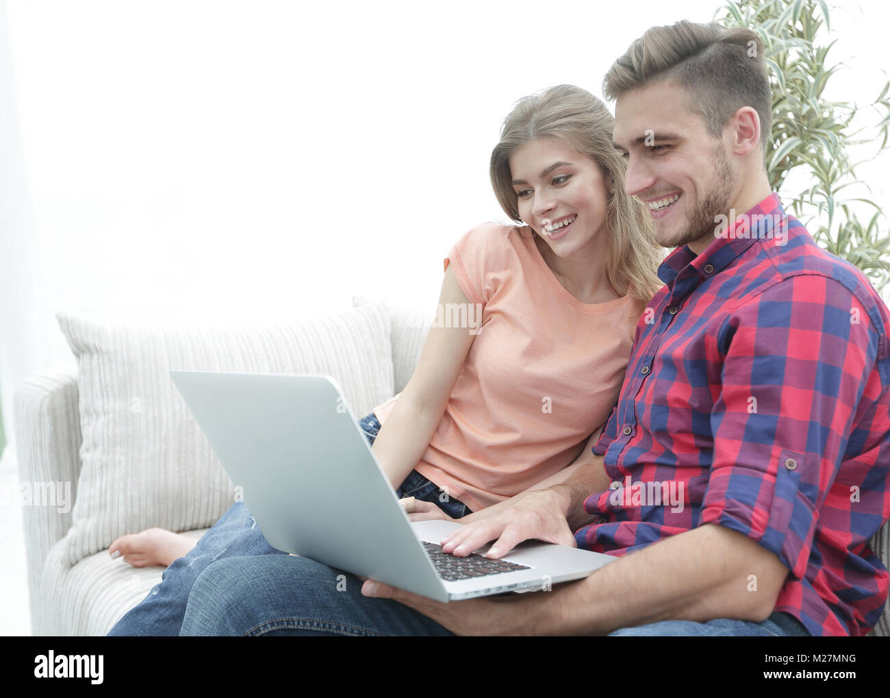 smiling young couple with laptop sitting on the couch Stock Photo - Alamy