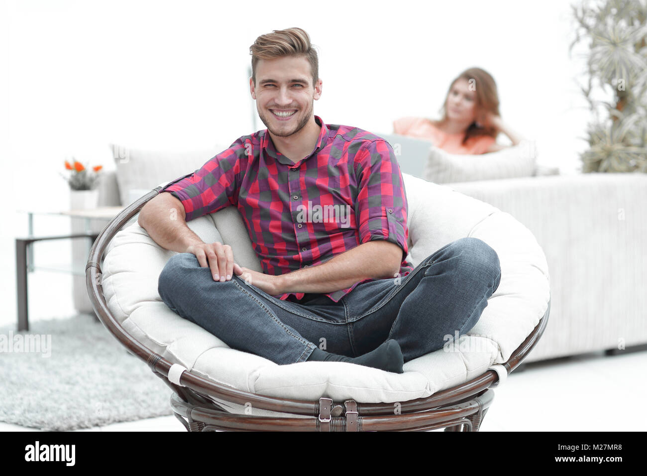 modern young man sitting in a big round chair on blurred background ...