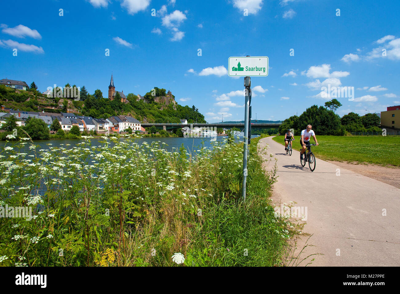 Cyclists on cycleway at riverside, place name sign of Saarburg at the ...