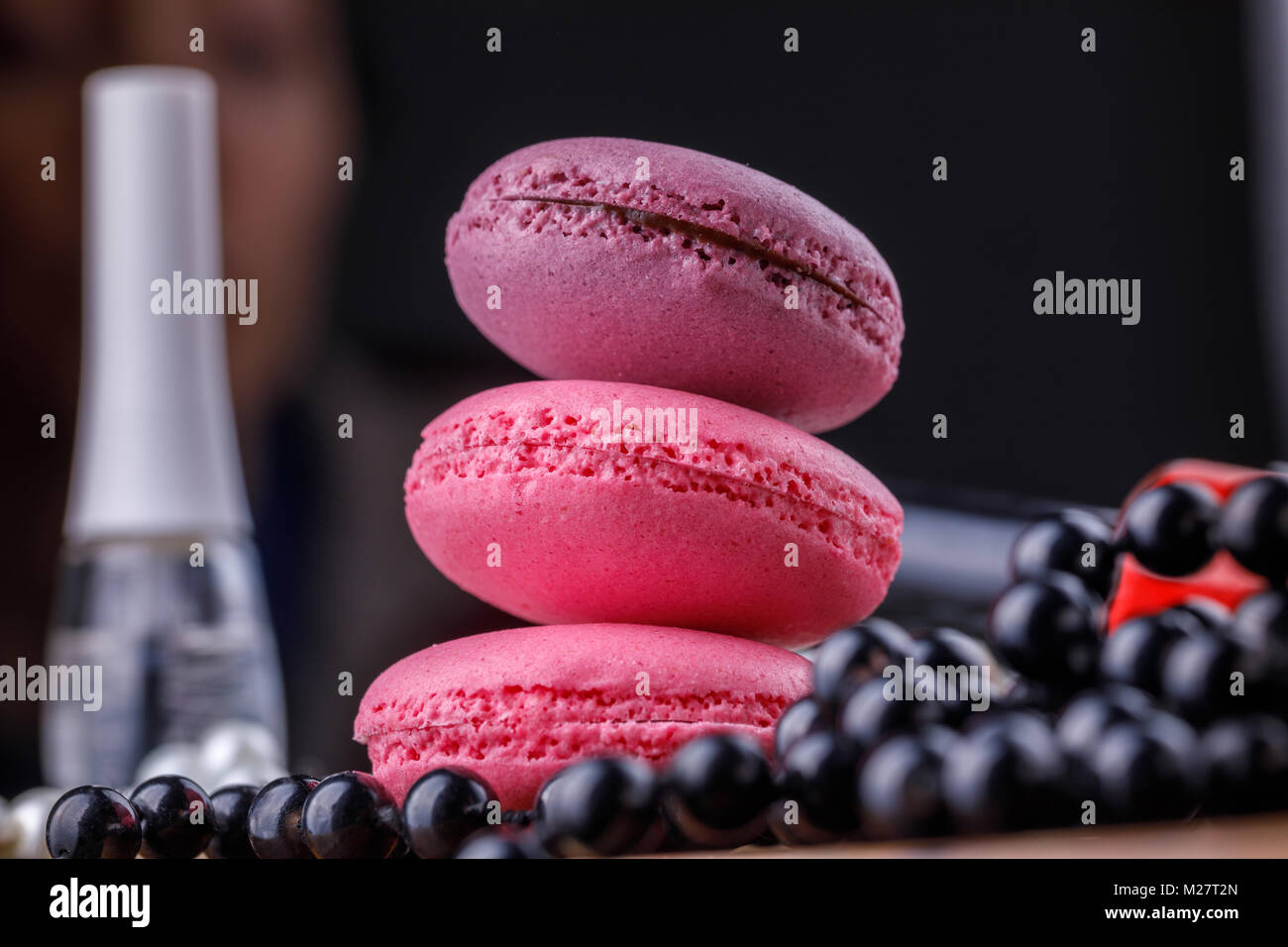 Pyramid of macaroons of pink shades on a wooden background with a tube ...