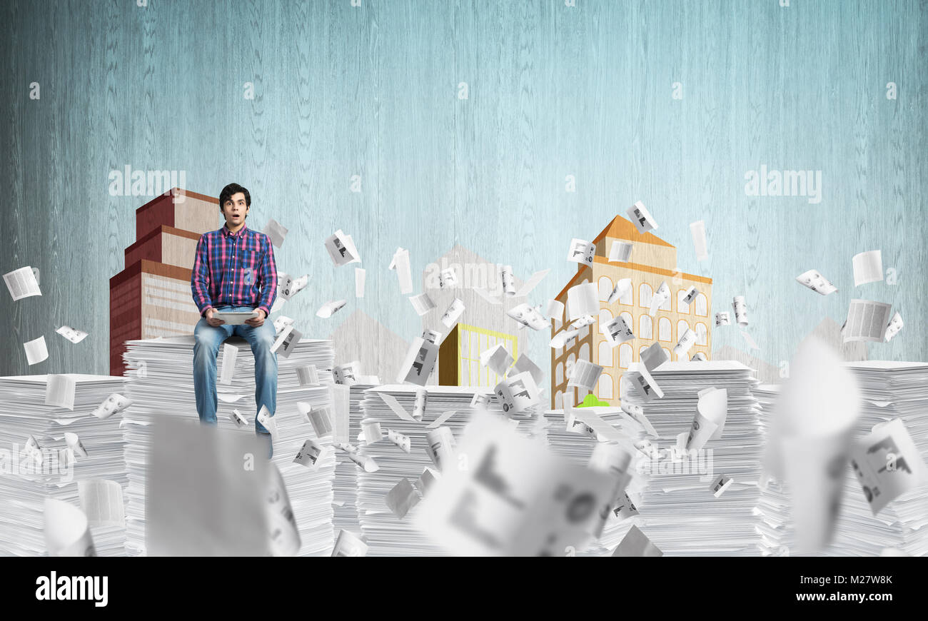Young man sitting on pile of paper documents Stock Photo - Alamy