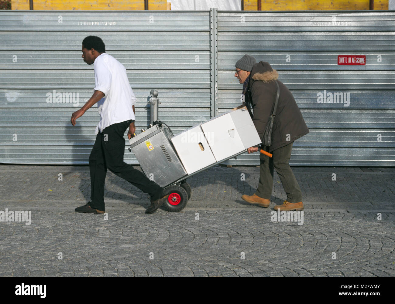 men pulling loaded cart on the street, Milan, Italy Stock Photo - Alamy