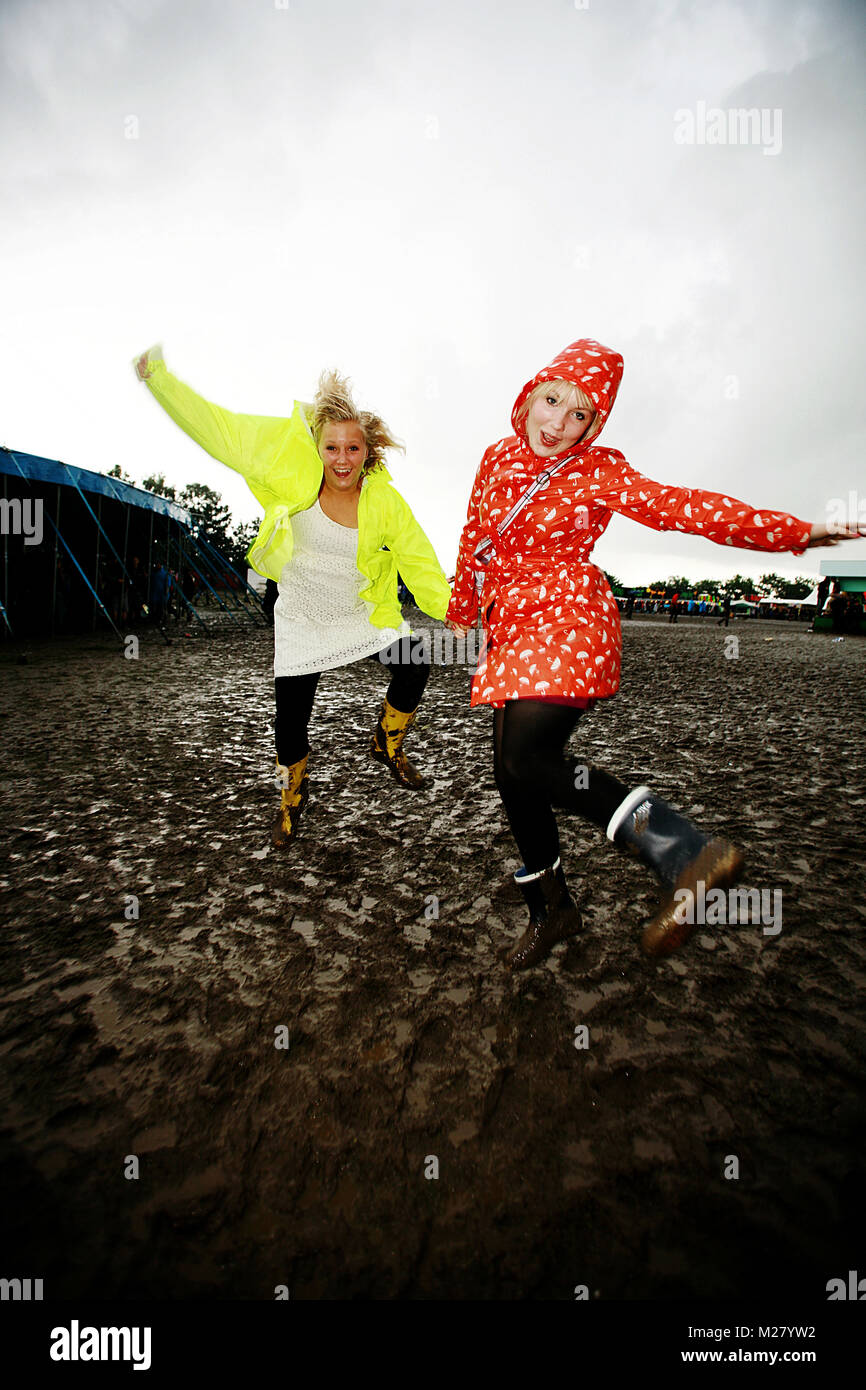 Twoyoung girls are having a great time dancing in the mud at a rainy ...