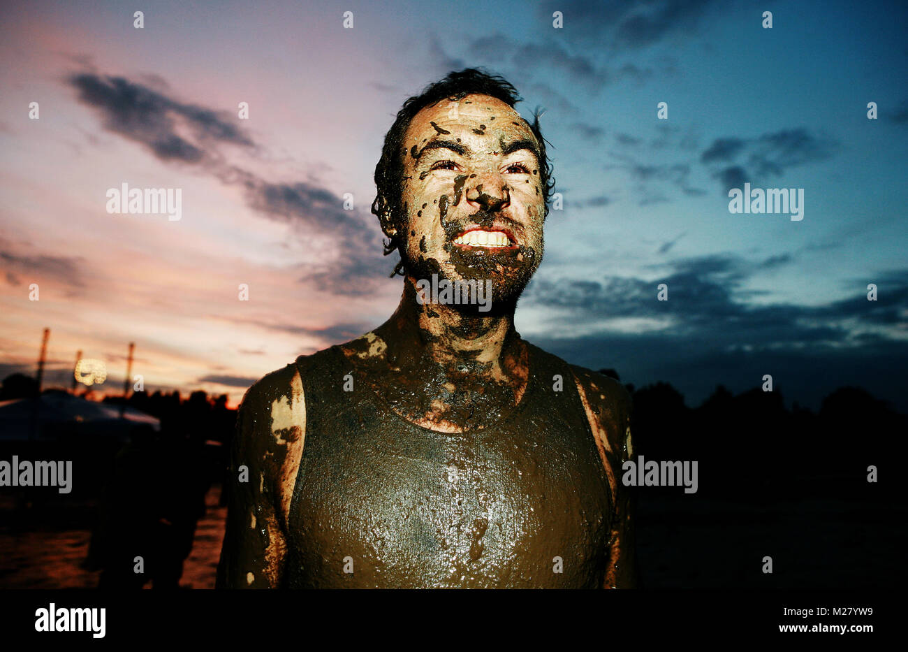 A happy festival guest takes the bad weather and mud with a smile at ...