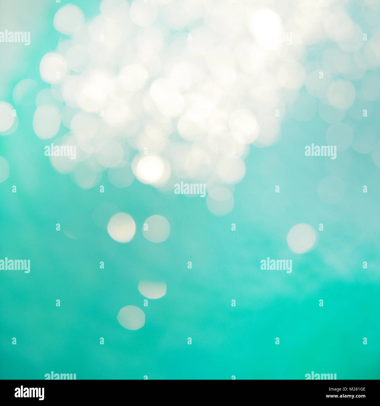 Soft focus bokeh light effects over a rippled, blue water background in ...
