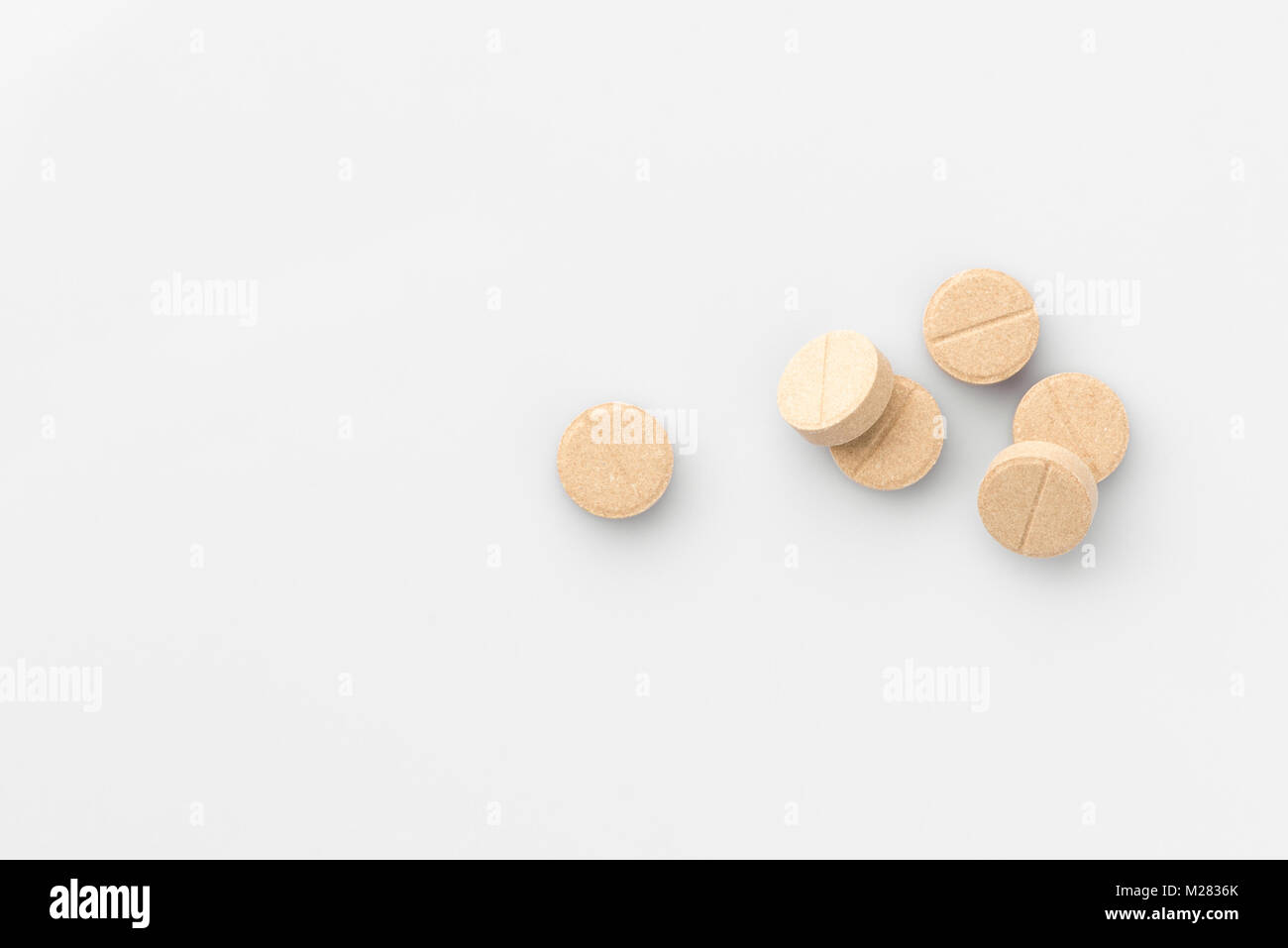 Many light beige medical tablets on a white background. The view from ...
