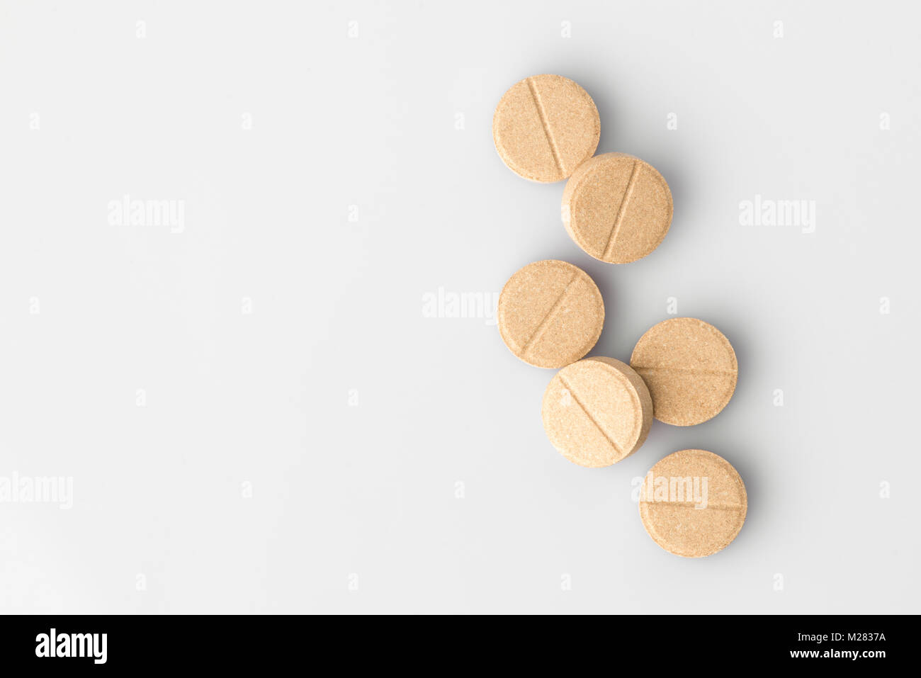 Pile light beige medical tablets on a light background. The view from ...