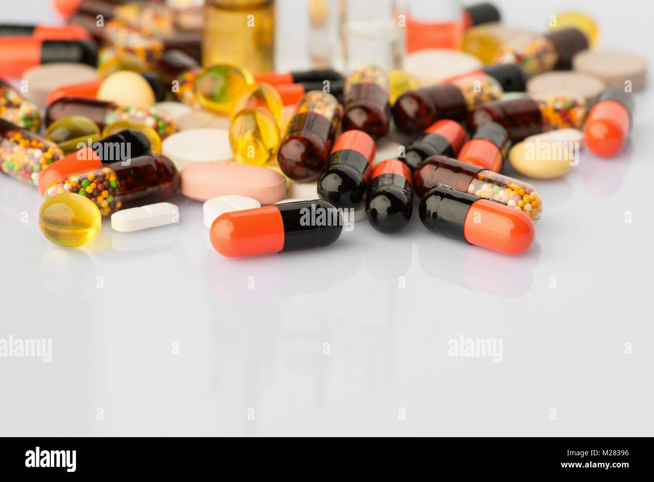 multi-colored tablets and capsules with reflection on blurred ...