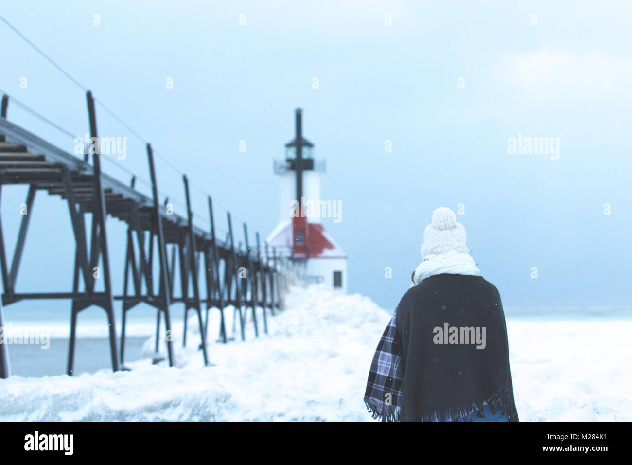 A woman looks out at the ice covered lighthouse of St. Joseph, Michigan ...