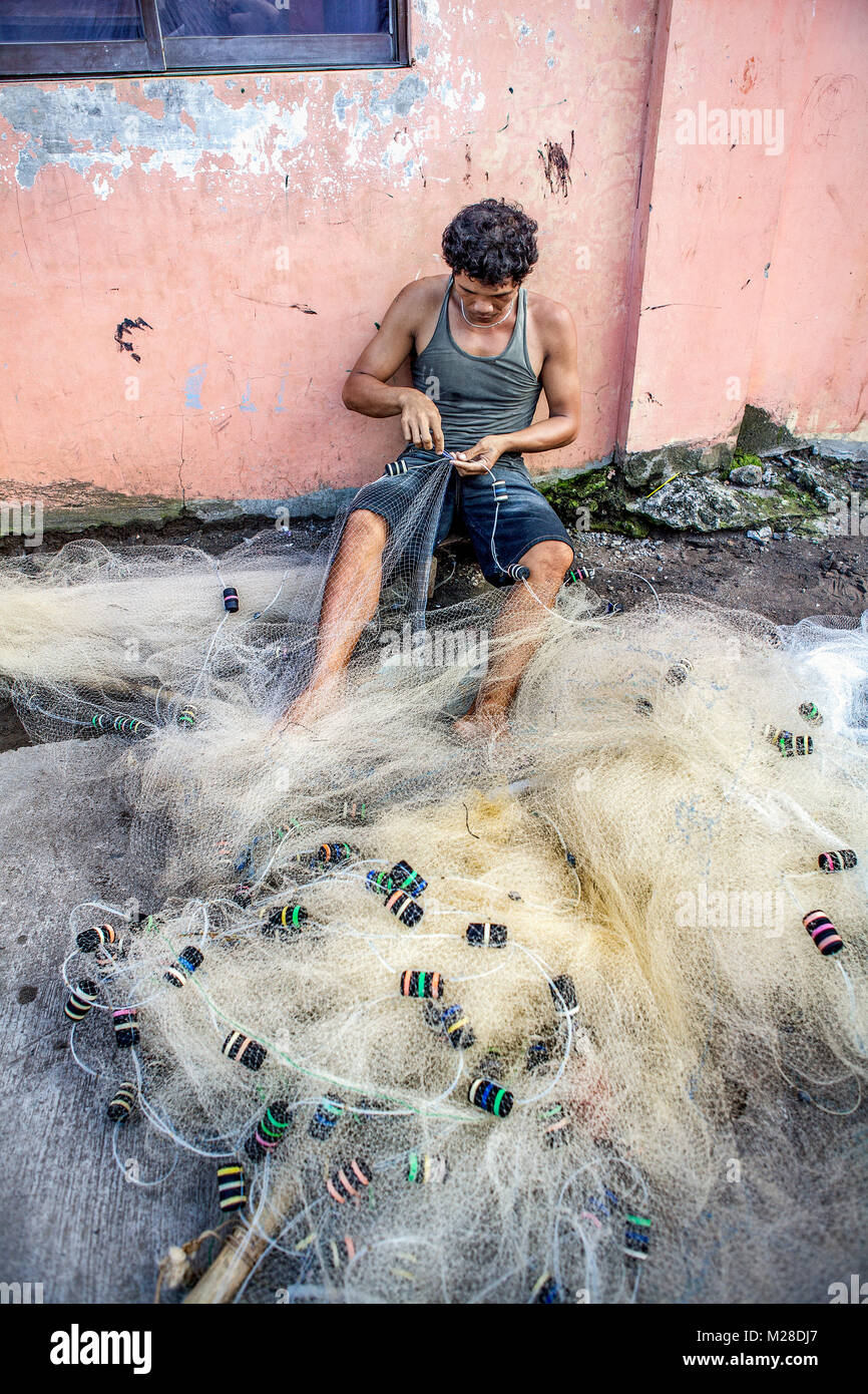 A Filipino fisherman sits mending his seine net, critical equipment for ...