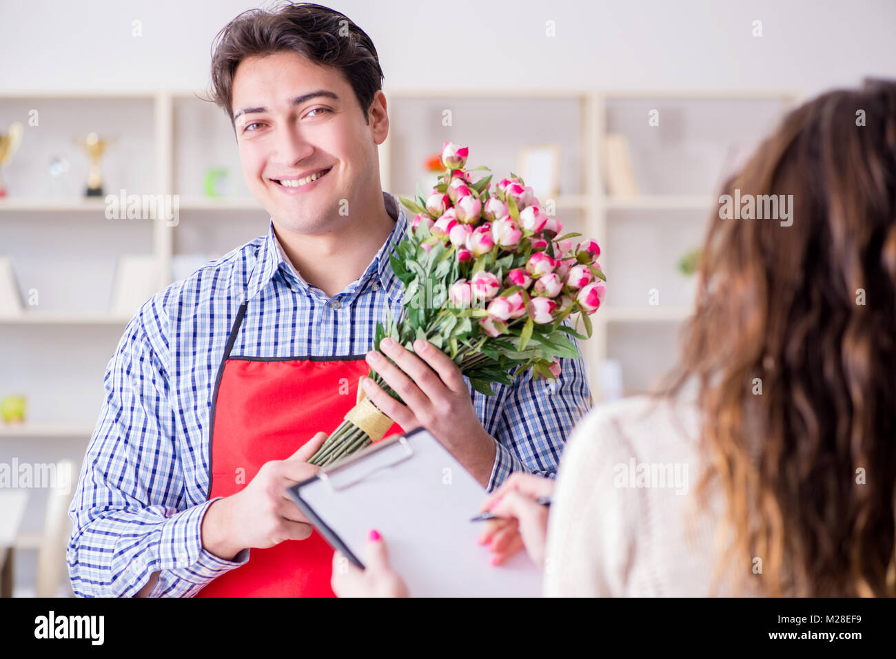 Flower shop assistant selling flowers to female customer Stock Photo ...