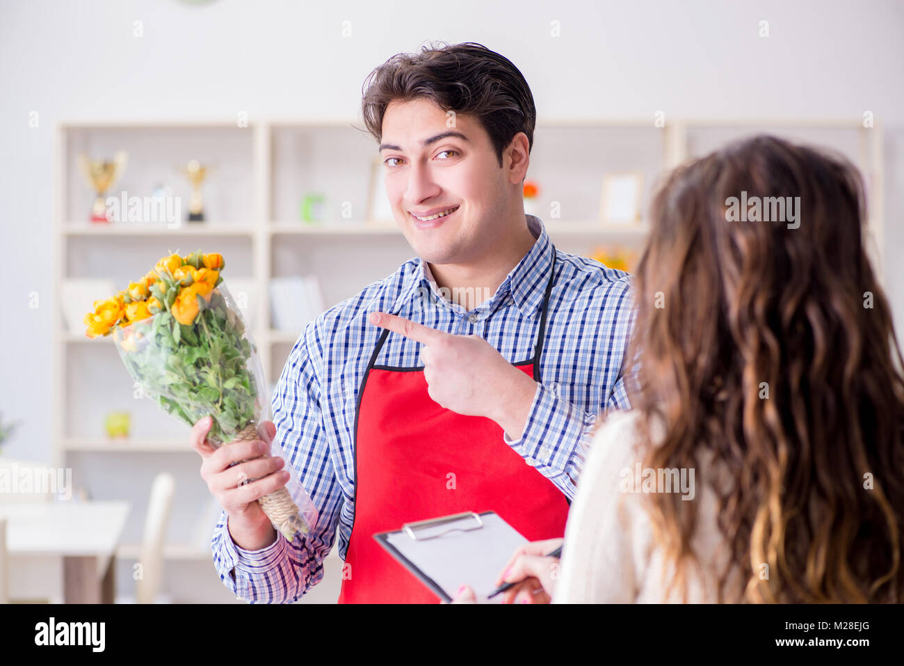 Flower shop assistant selling flowers to female customer Stock Photo ...