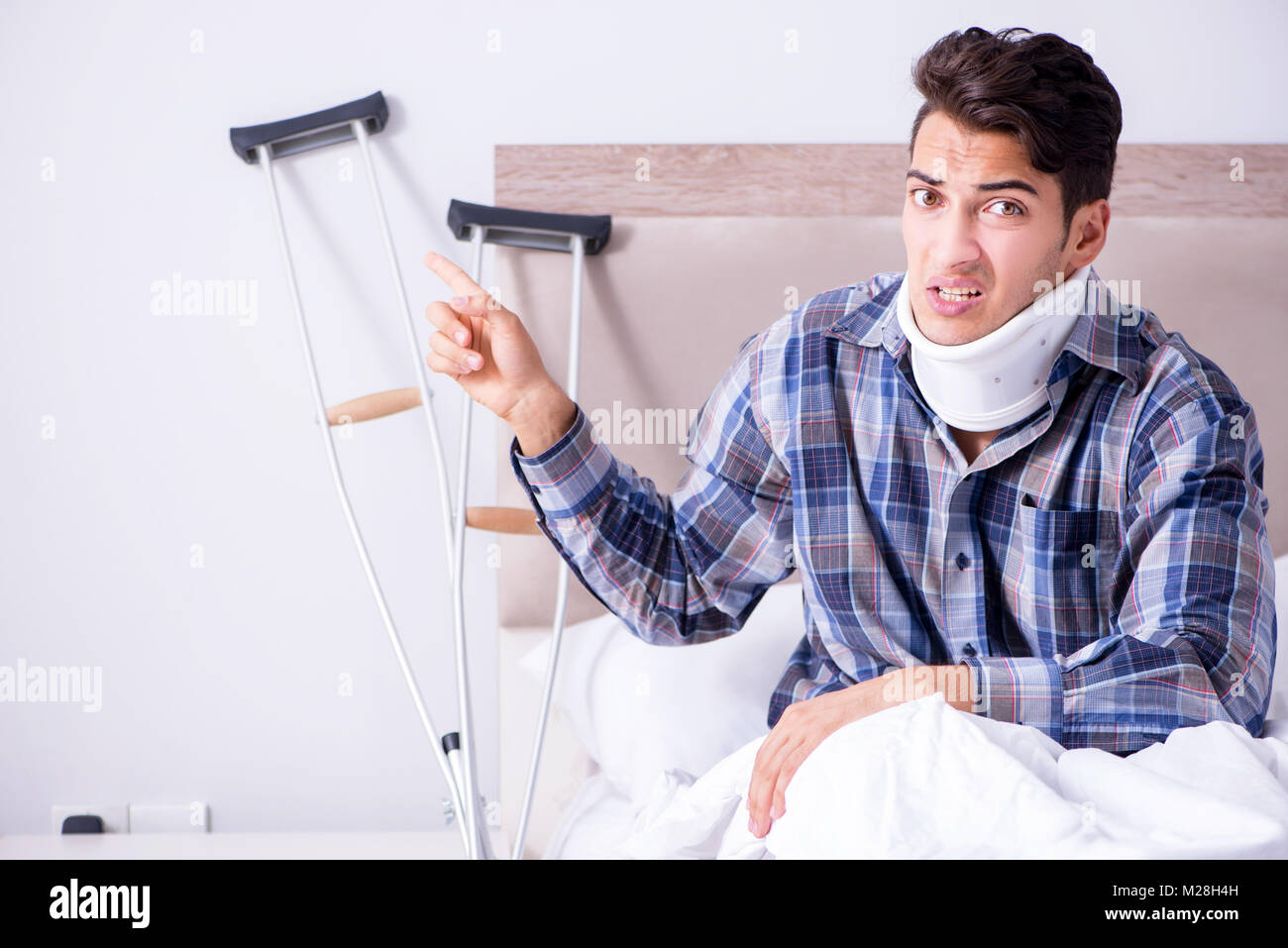 Injured man in bed at home with crutches Stock Photo - Alamy
