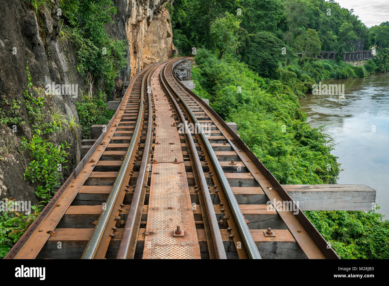Old railroad tracks on bridge beside cliff rock Stock Photo - Alamy