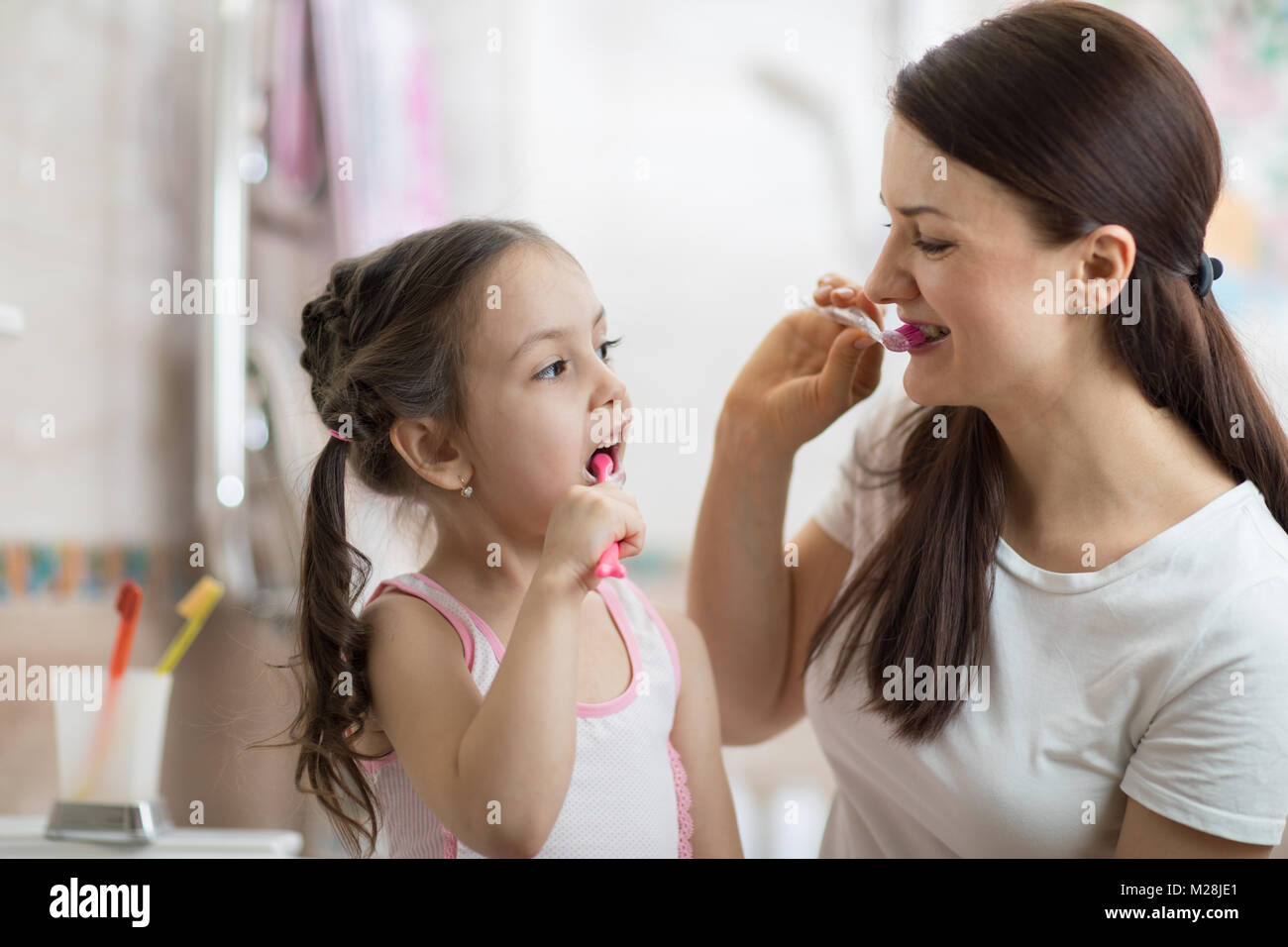mother teaching kid daughter teeth brushing in bathroom Stock Photo - Alamy