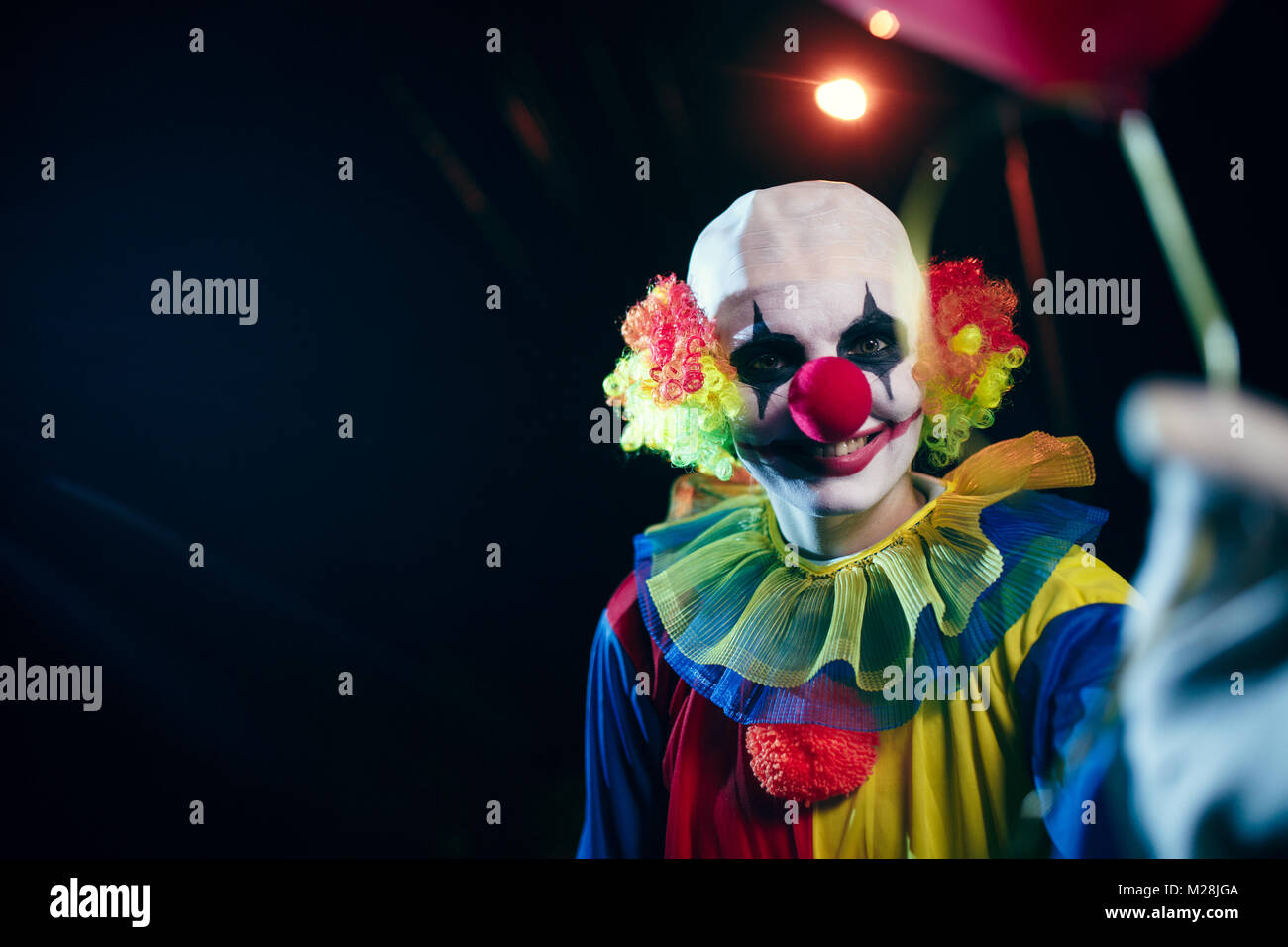 Photo of clown with red balloon at night on street Stock Photo - Alamy