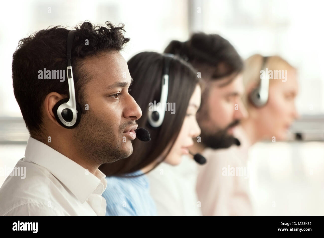 Black call center operator with colleagues. Side view of line of call ...