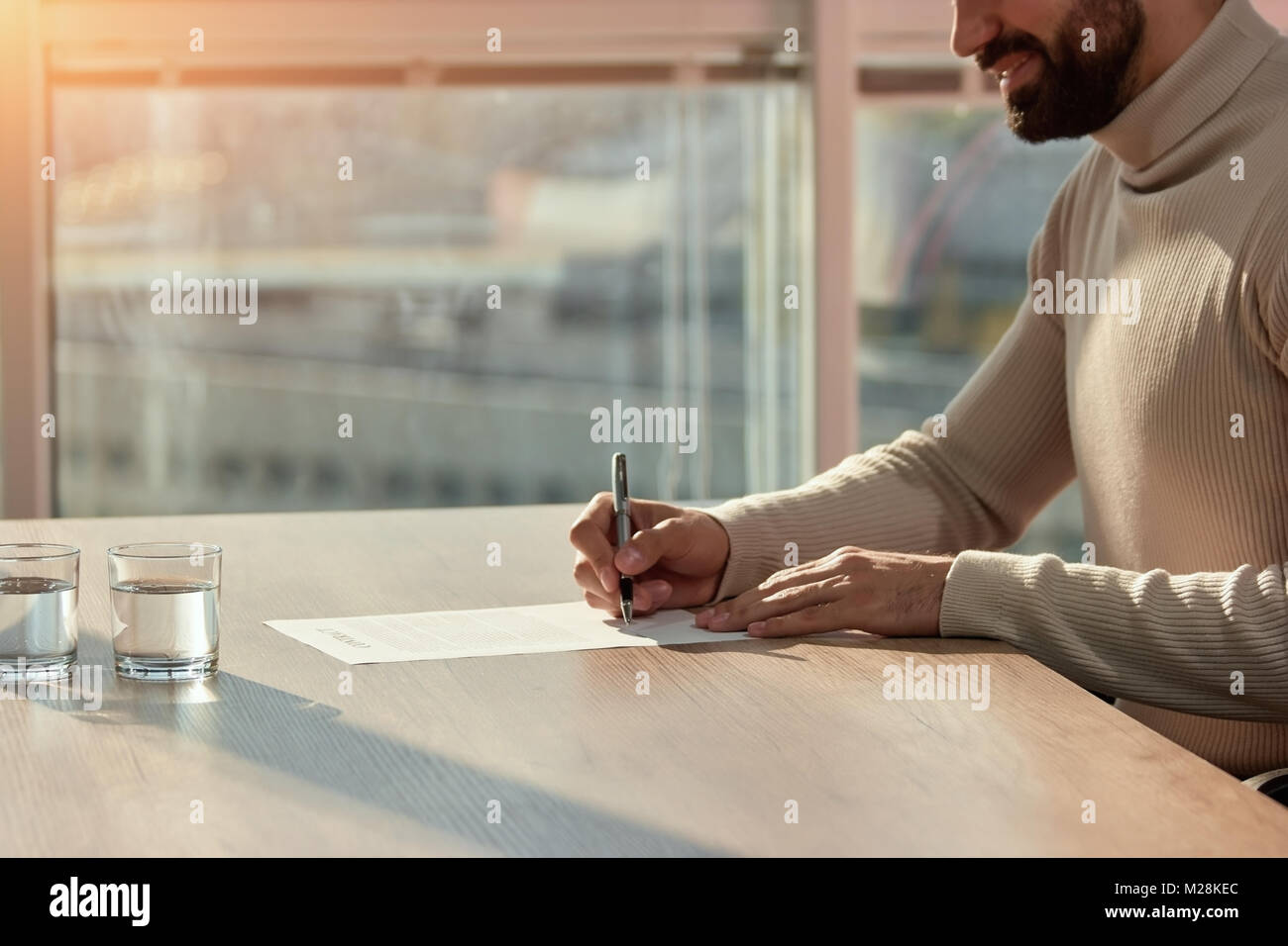 Berded man signing contract at office desk. Side view caucasian man ...
