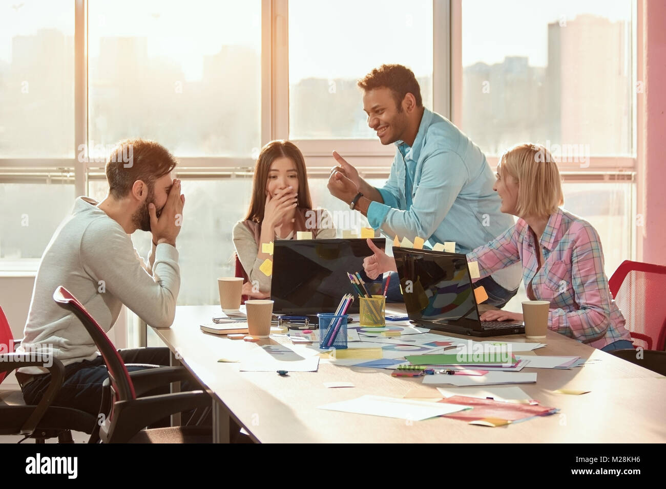 Creative designers fooling around at office desk. Mixed raced group ...
