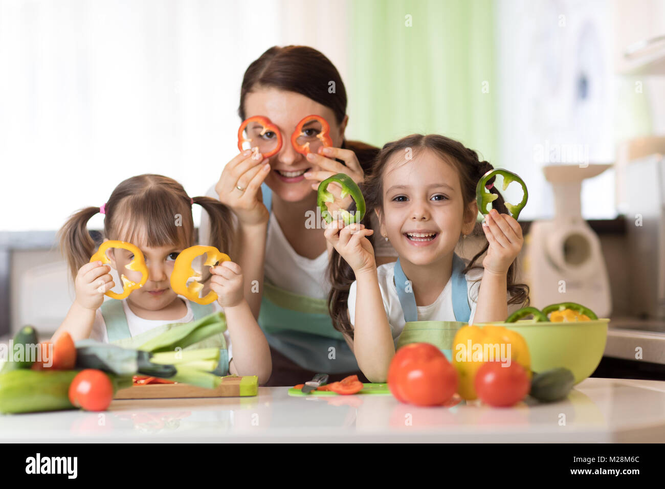 Happy family mom and kids having fun with food vegetables at kitchen ...