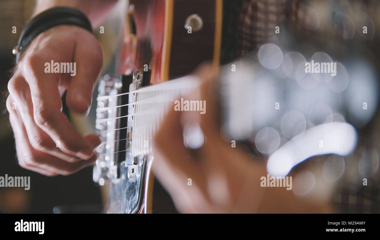 Male musician plays the guitar, hands close up, focus on the guitar ...