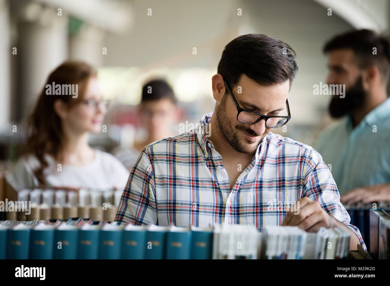 Male student picking a book in a library Stock Photo - Alamy