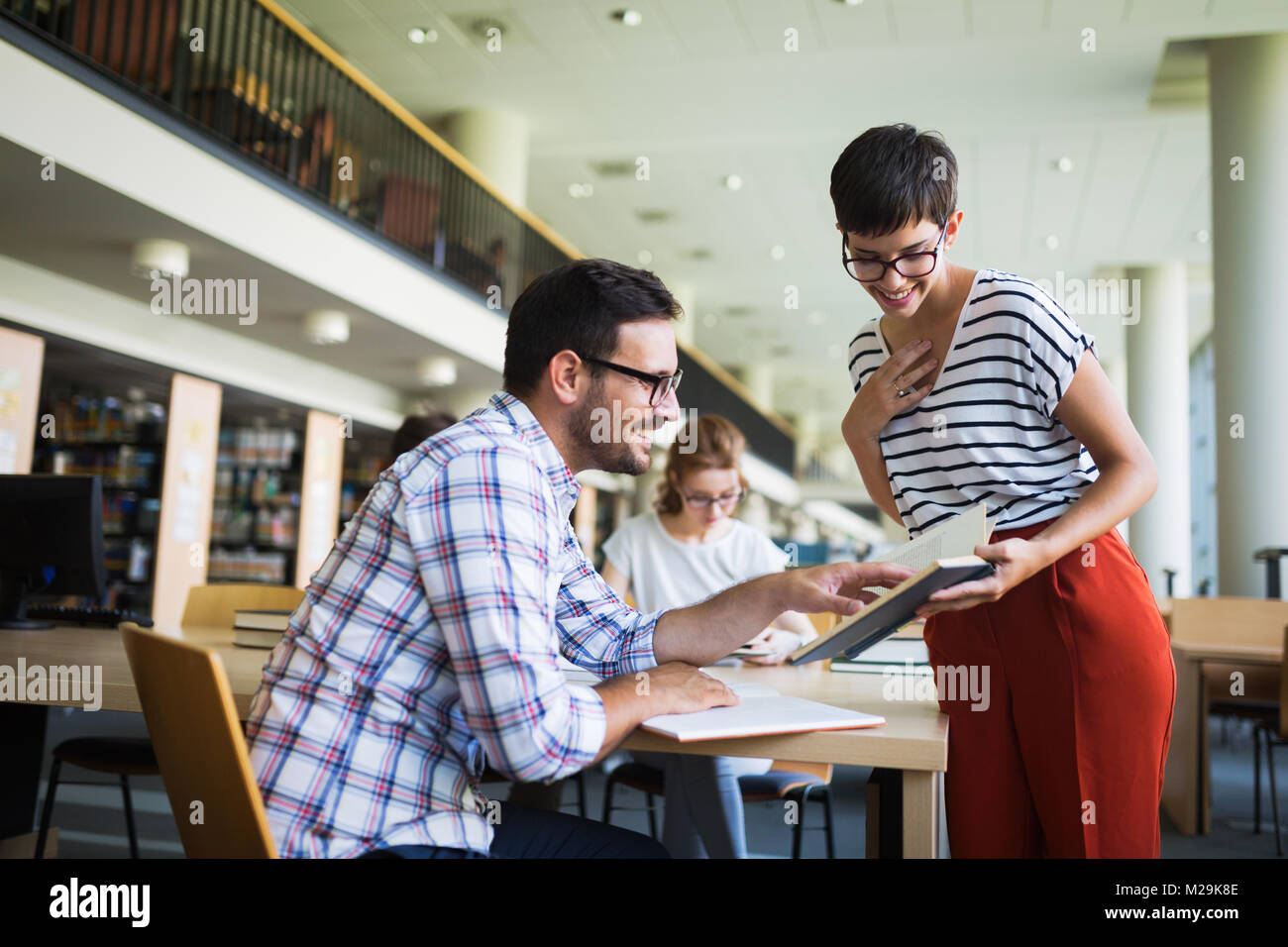 Young happy students sitting in library Stock Photo - Alamy