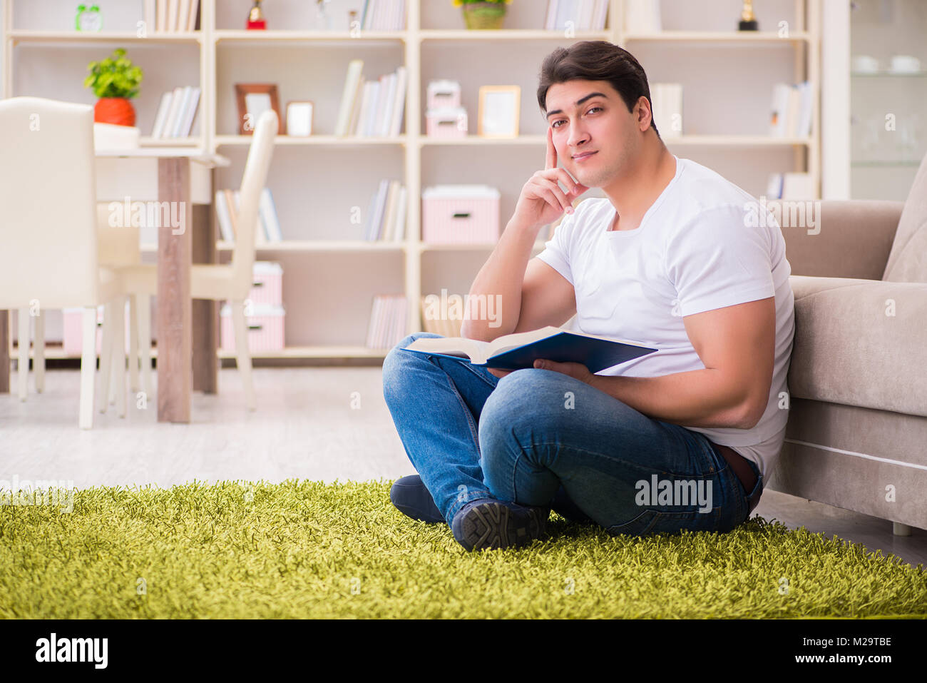Man reading book at home on floor Stock Photo - Alamy