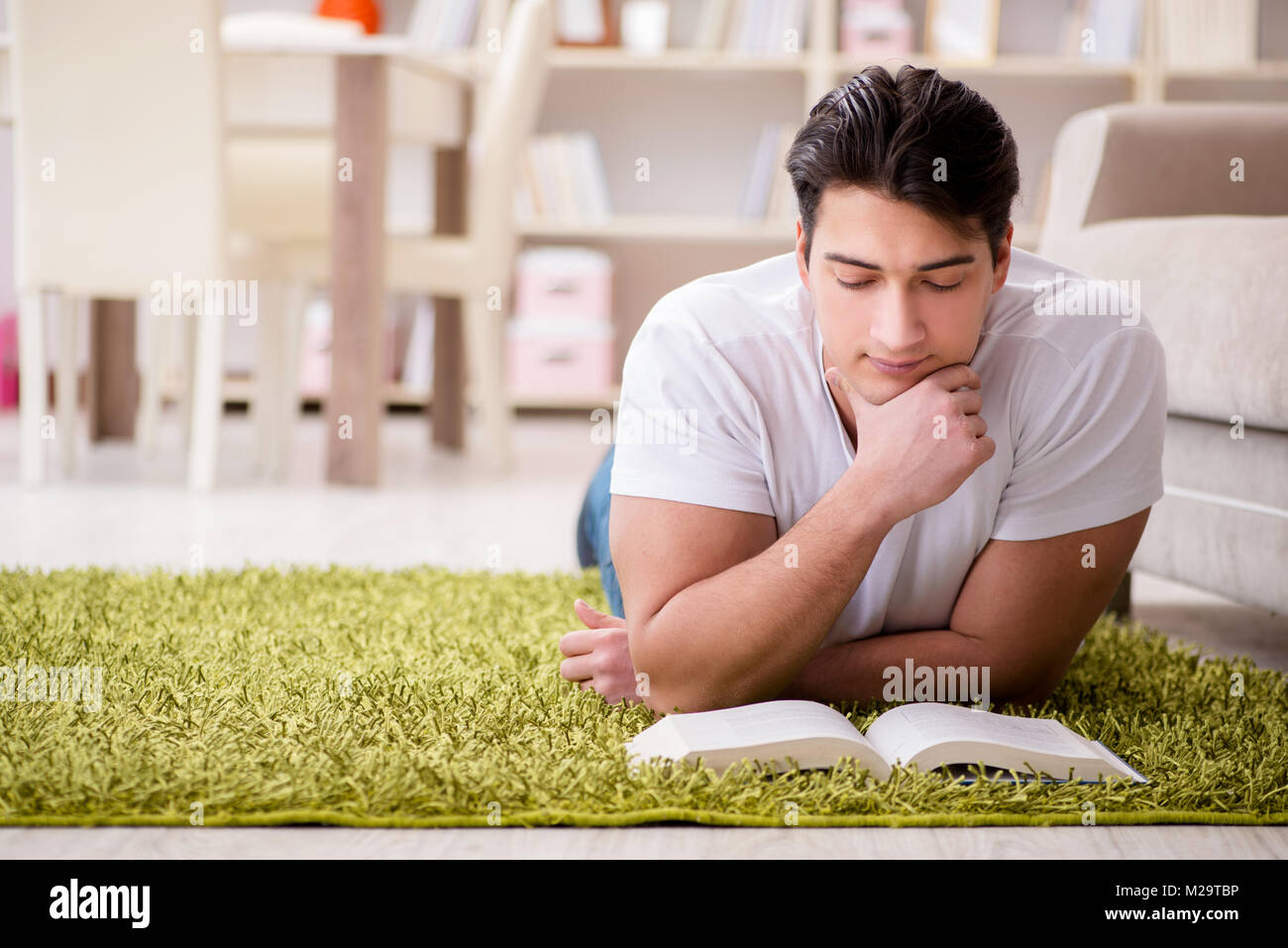 Man reading book at home on floor Stock Photo - Alamy