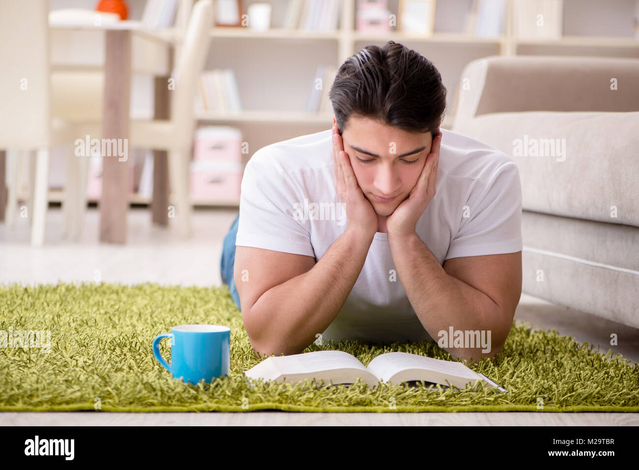 Man reading book at home on floor Stock Photo - Alamy