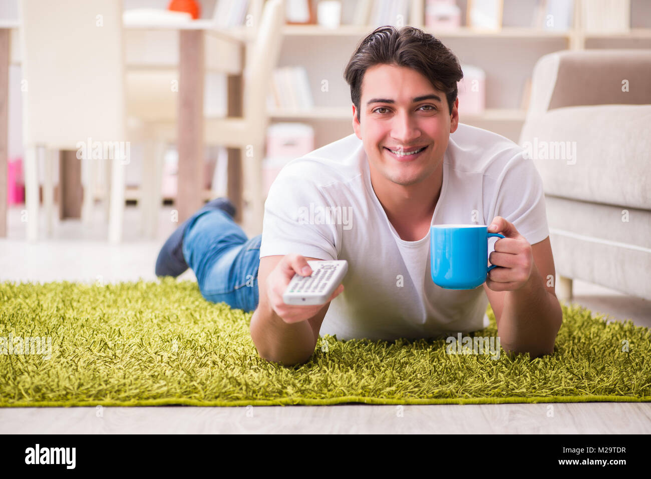 Man watching tv at home on floor Stock Photo - Alamy