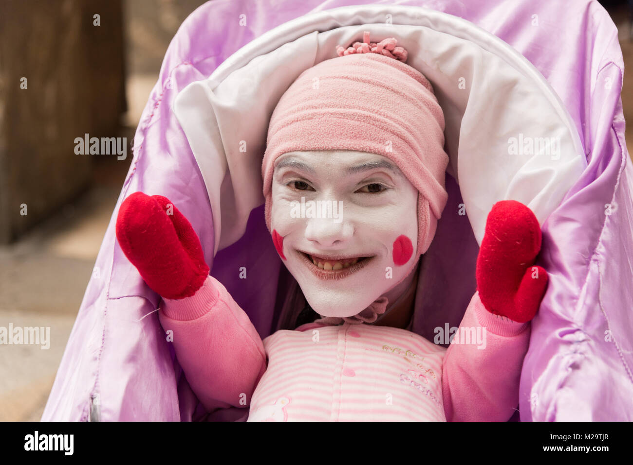 A street performer or busker dressed as a baby in a pram in Bologna ...