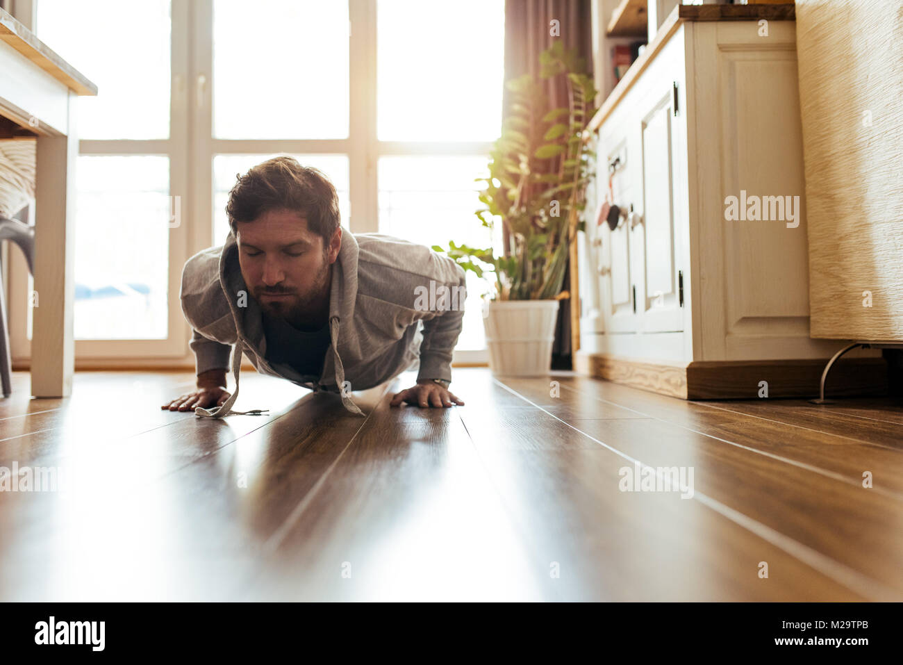 Fit young man in sportswear straining while doing pushups on the floor ...