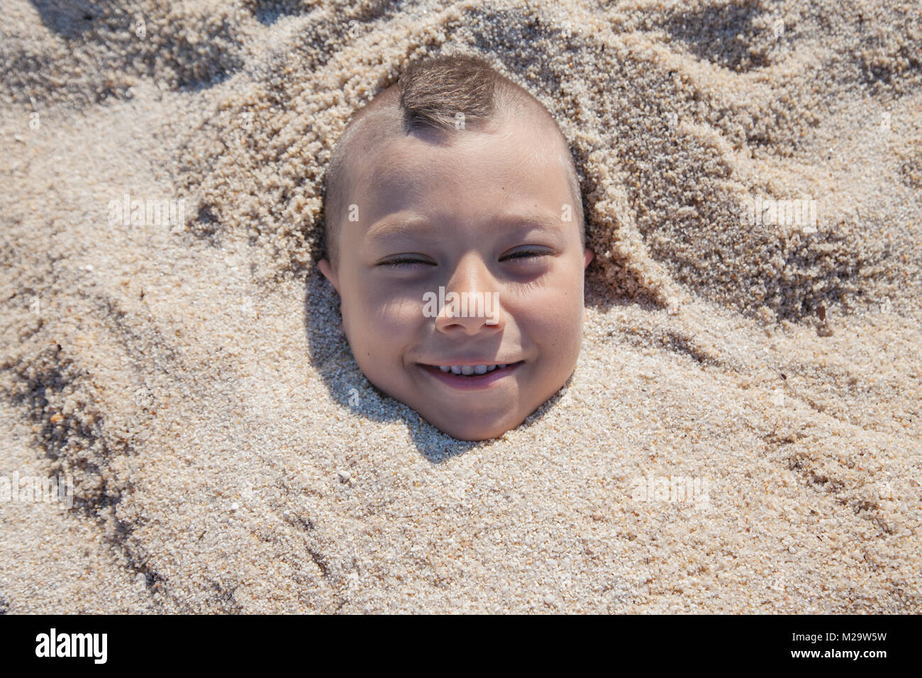 A close-up of a child s face, body buried under the sand Stock Photo ...