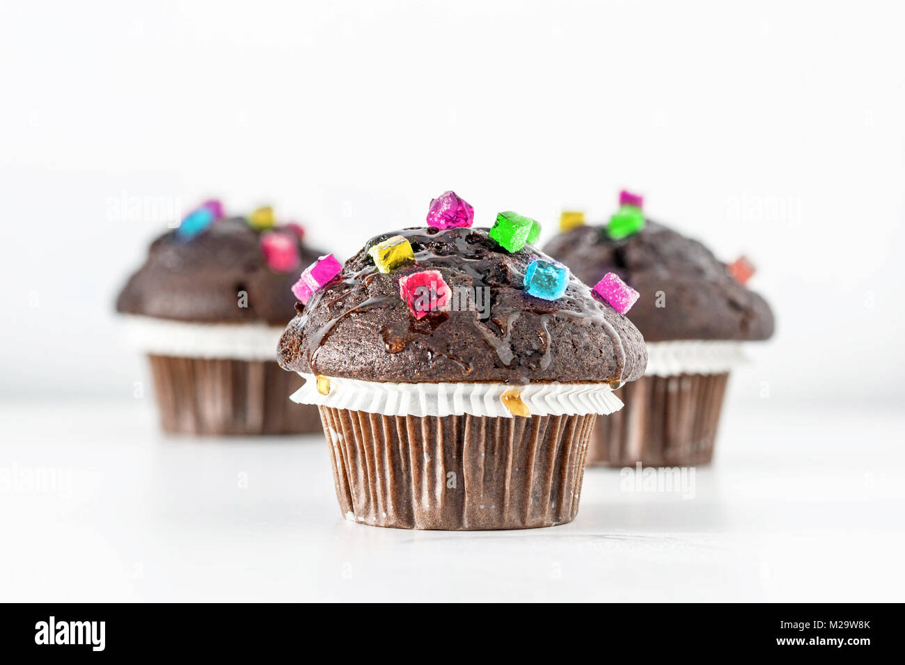 Funny Chocolate Muffins decorated with colorful candies on white ...