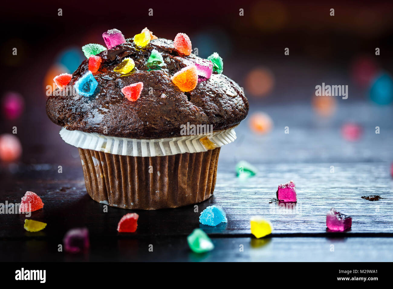 Delicious and funny Chocolate Muffin with candies on wooden table ...