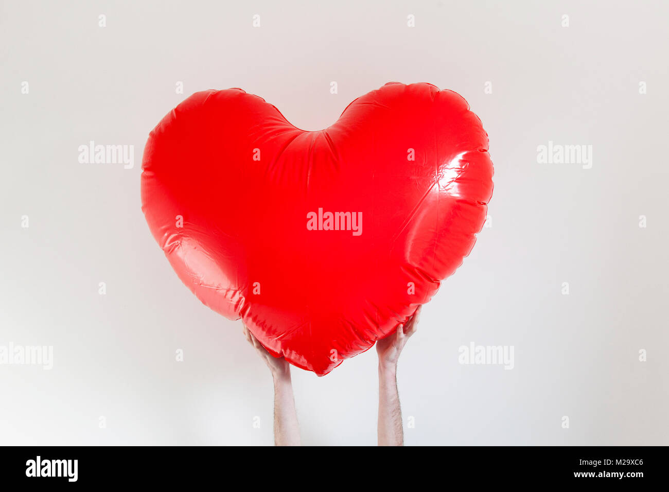 Hands holding a large inflatable heart shape Stock Photo - Alamy